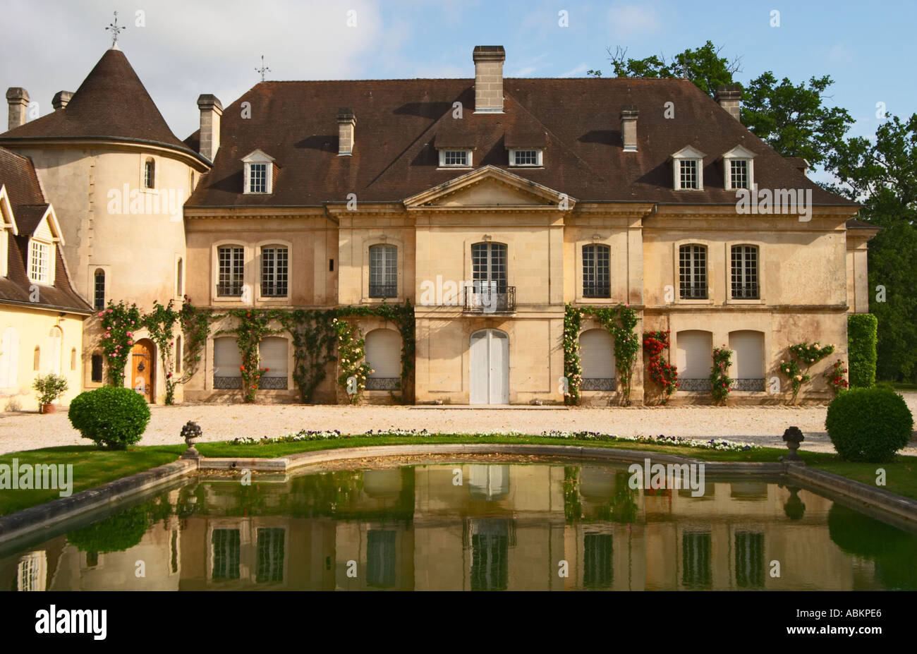 The main chateau building with its tower and a pond showing a ...