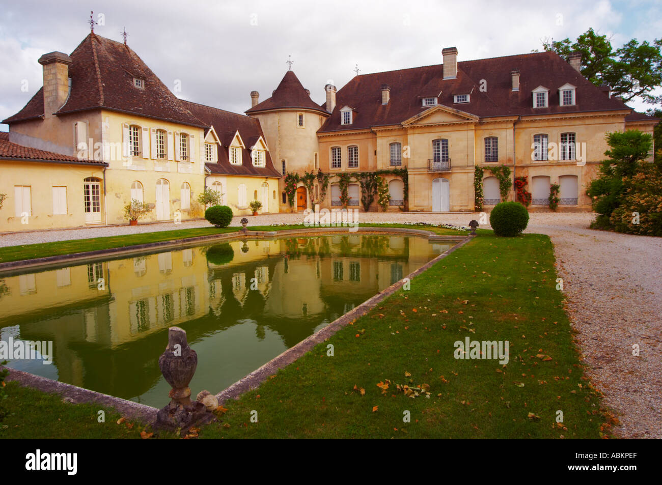 The main chateau building with its tower and a pond showing a ...