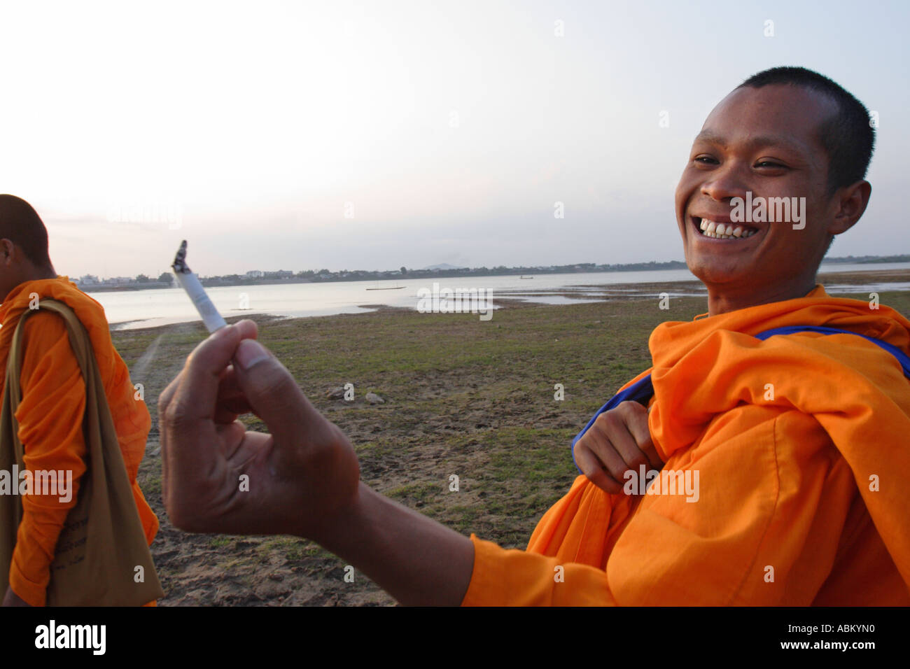 Young Buddhist monk smoking by the Mekong river in Laos Stock Photo - Alamy