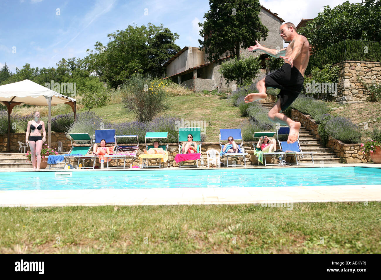 A young athletic man jumping into a swimming pool in a villa in Tuscany ...