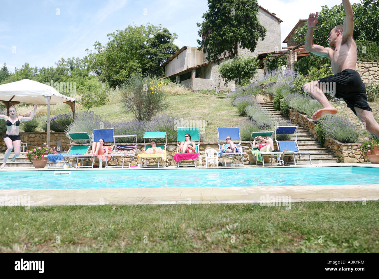 A young athletic man jumping into a swimming pool in a villa in Tuscany ...