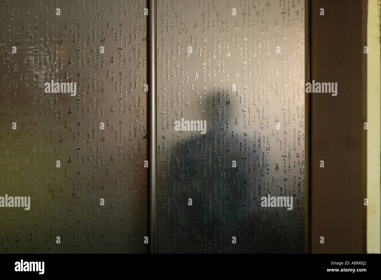 Man standing behind a glass door inscribed with chinese ideograms ...