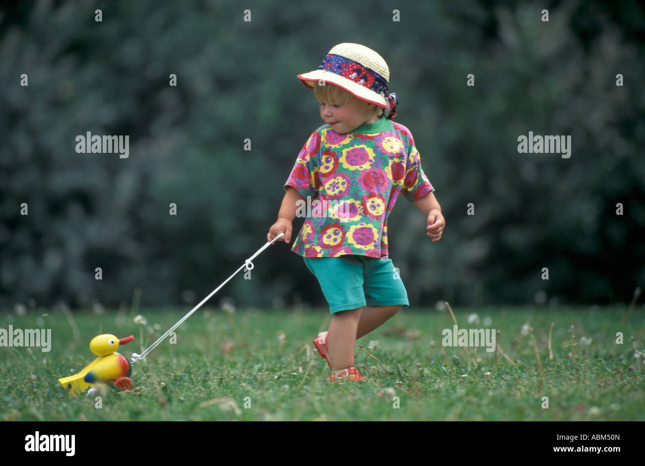 Little girl walking with her toy duck Stock Photo - Alamy