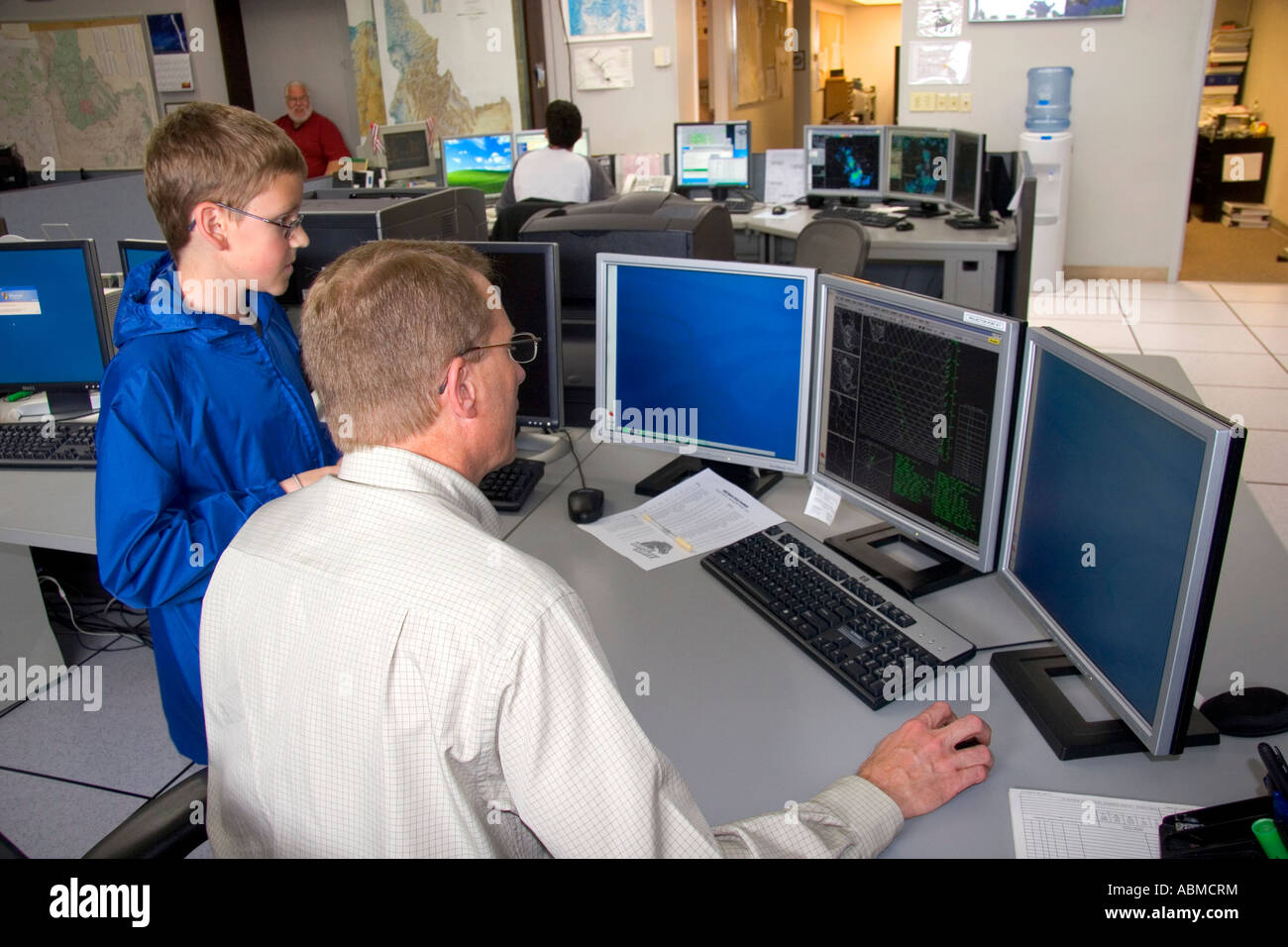 Weather maps on computer screens and a meteorologist at the National ...