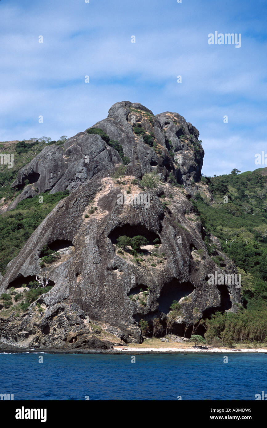 Volcanic rocks with caves rise from the beach in this island picture ...