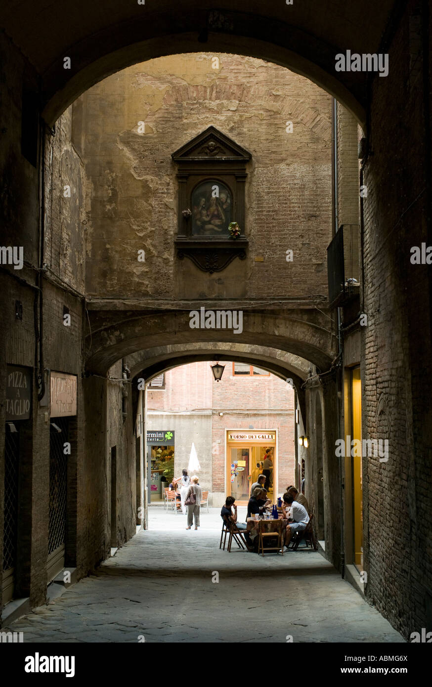 People relaxing in atmospheric side street in Siena, Italy Stock Photo ...