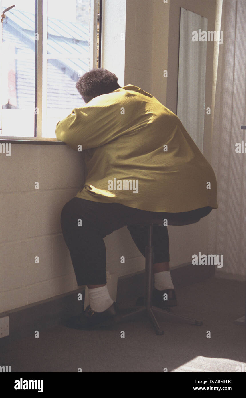 obese woman sitting on chair in room looking out Stock Photo - Alamy