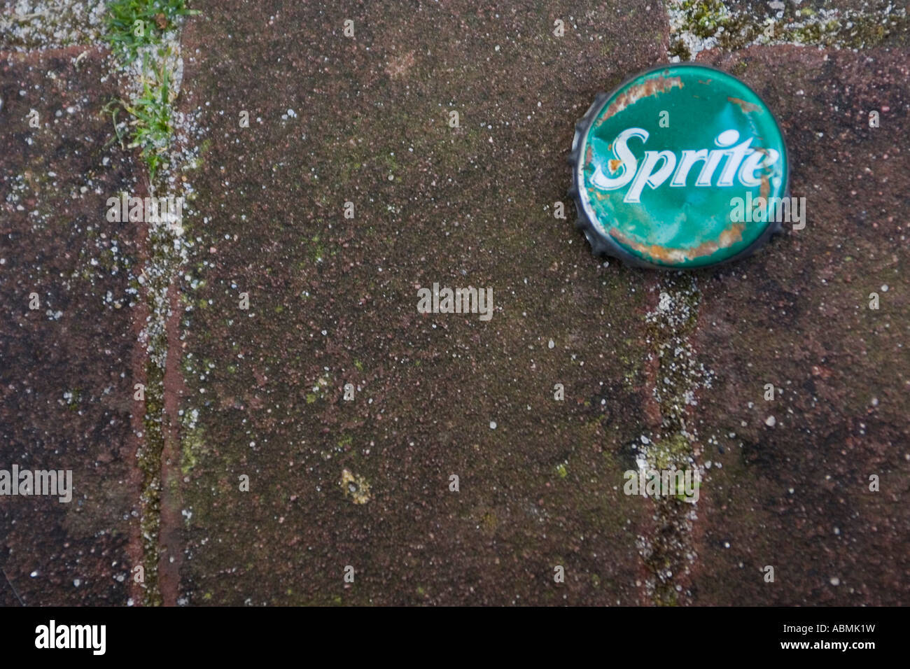 Crushed metal cap of a Sprite bottle, left on the street Stock Photo ...