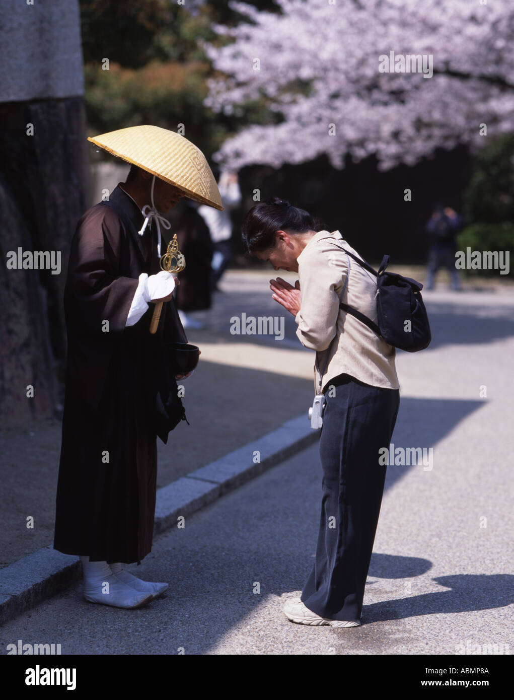 Japanes woman gives alms to a buddhist monk inside the grounds of Osaka ...