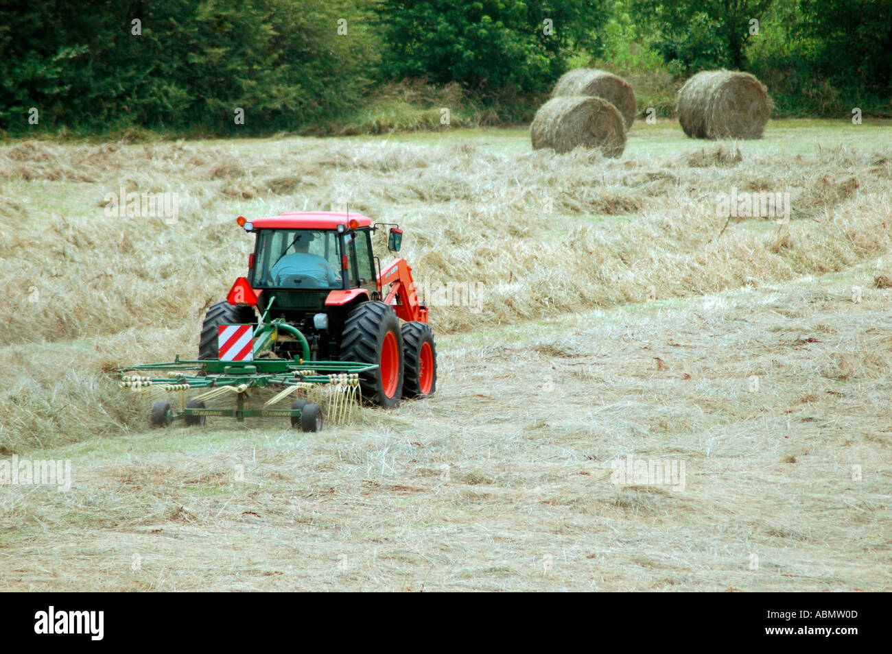 tractor working on farm Cutting and rolling hay for bailing in squares ...