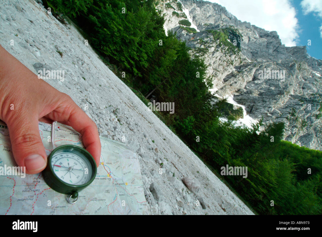 hand of a wanderer hiker in the mountains with a compass and a map ...