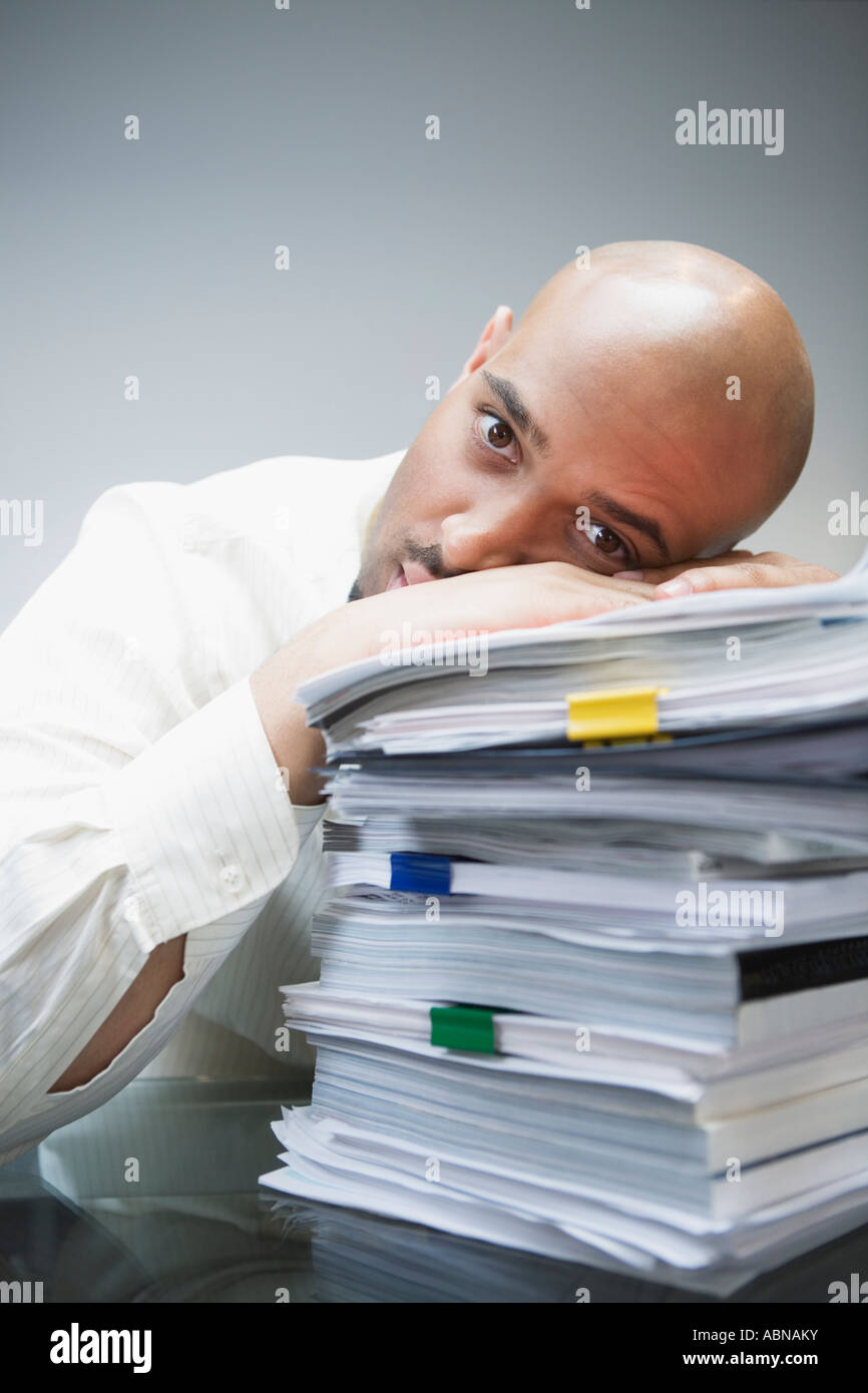 Businessman leaning on pile of work Stock Photo - Alamy