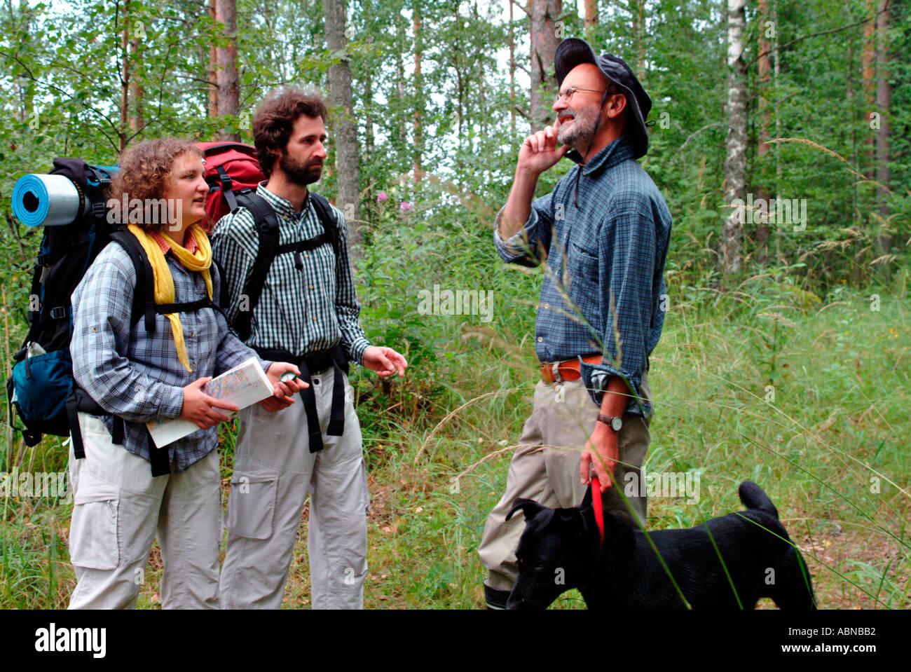 young couple hiking in the nature talking with a man with a dog MR ...