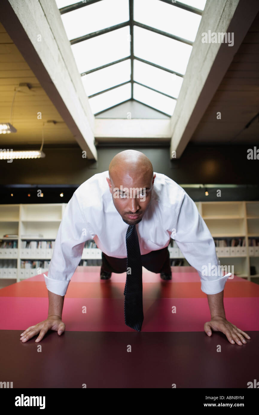 Businessman doing push-ups on conference table Stock Photo - Alamy