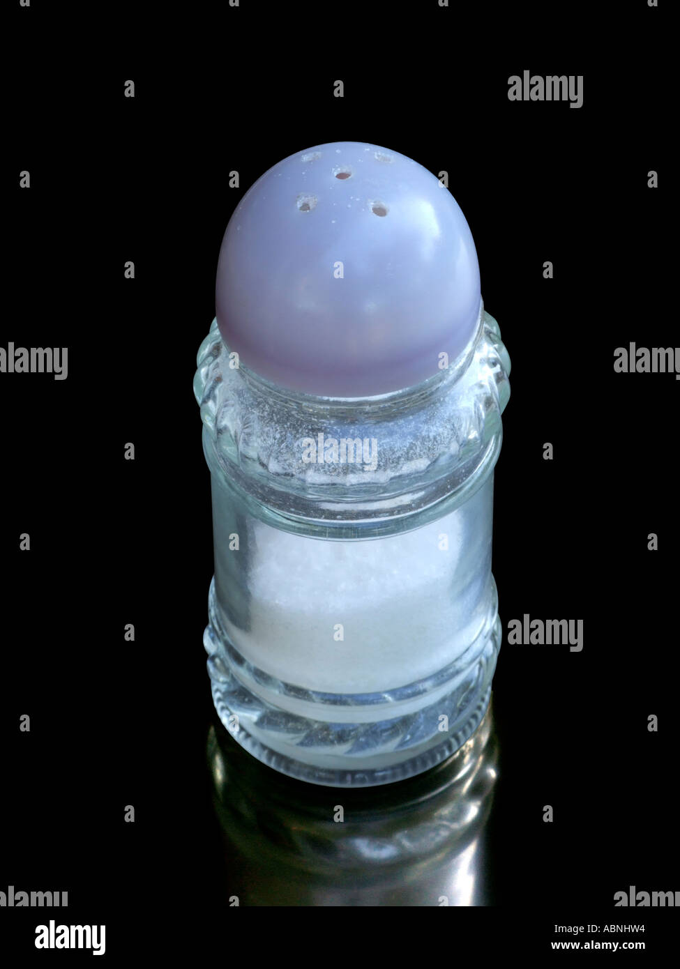 Salt shaker made of glass with plastic top on a black background with ...