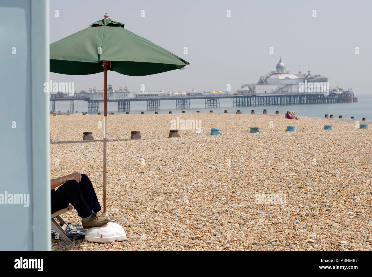 Eastbourne beach sunbather with parasol and pier Stock Photo - Alamy