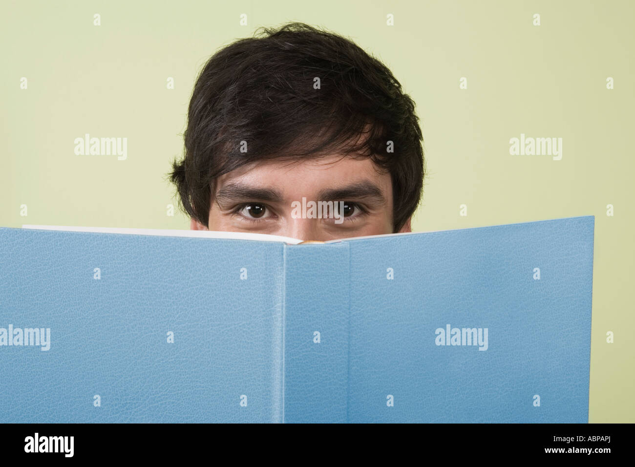 Man peering over book Stock Photo - Alamy
