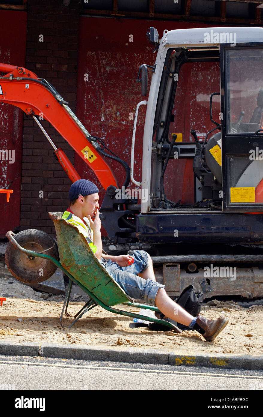 British Worker having a break from his job by resting in a wheelbarrow ...