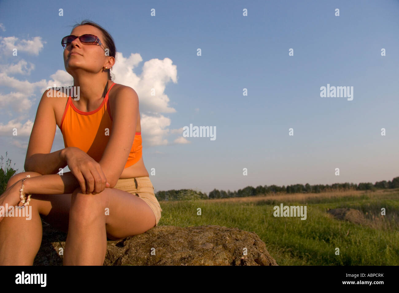 Beautiful girl sitting on the stone in sunset lighting Stock Photo - Alamy