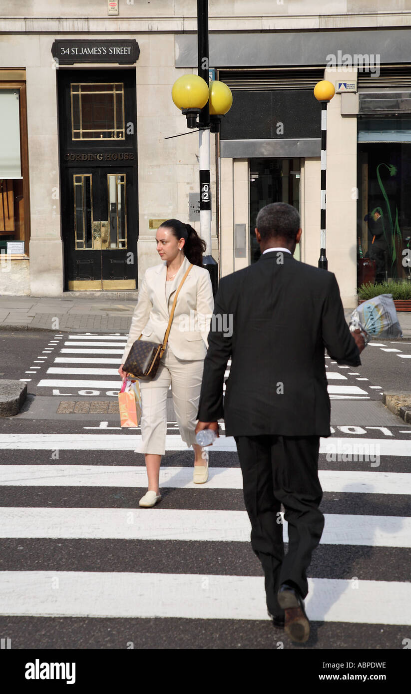 A man and woman walk across a pedestrian crossing in central London ...