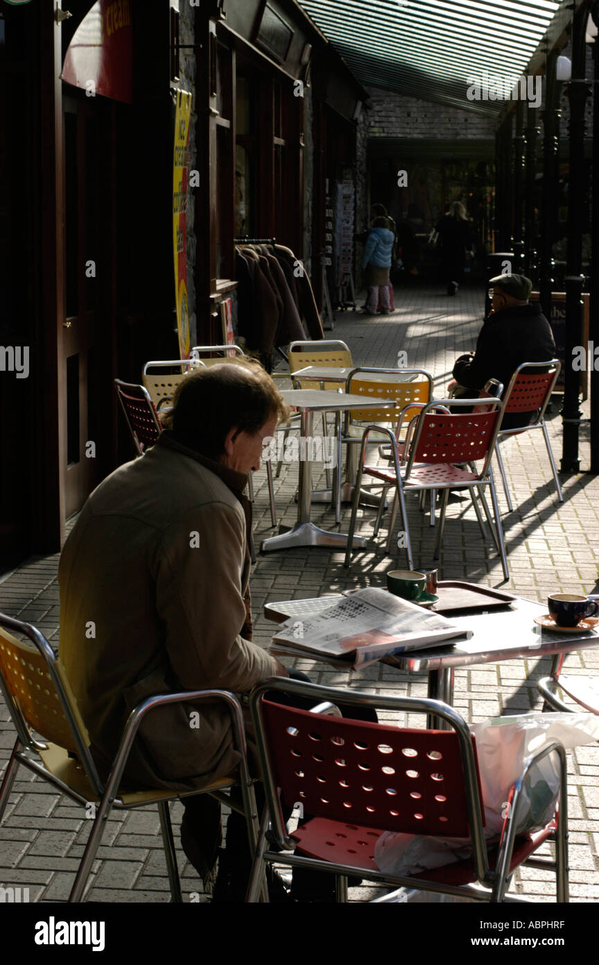 Man sitting alone and reading a newspaper in the morning sun, outdoor ...