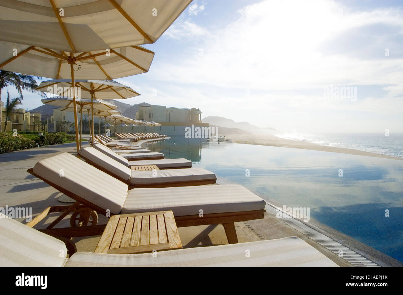 Empty chaises on infinity pool Stock Photo - Alamy
