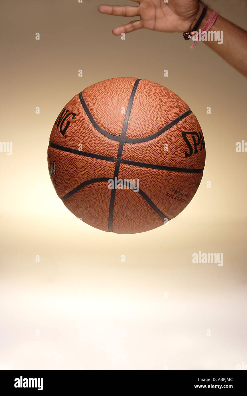 Hand releasing one brown color round basketball on plain background ...