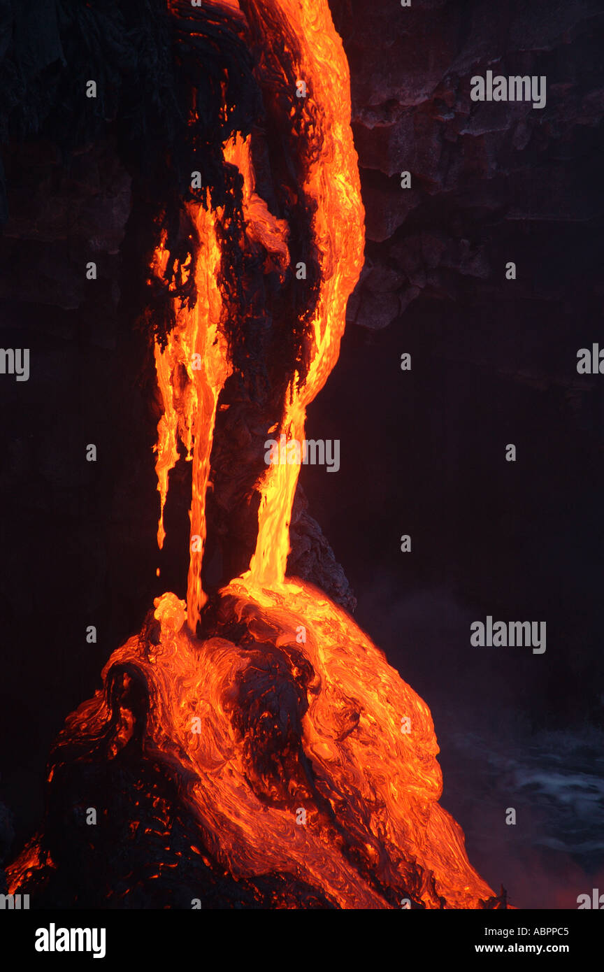 Cascade of lava forms a pillar of lava as it enters the water at the ...