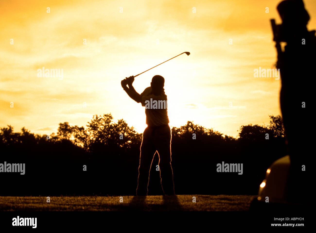 Golfer teeing off at sunrise Stock Photo - Alamy
