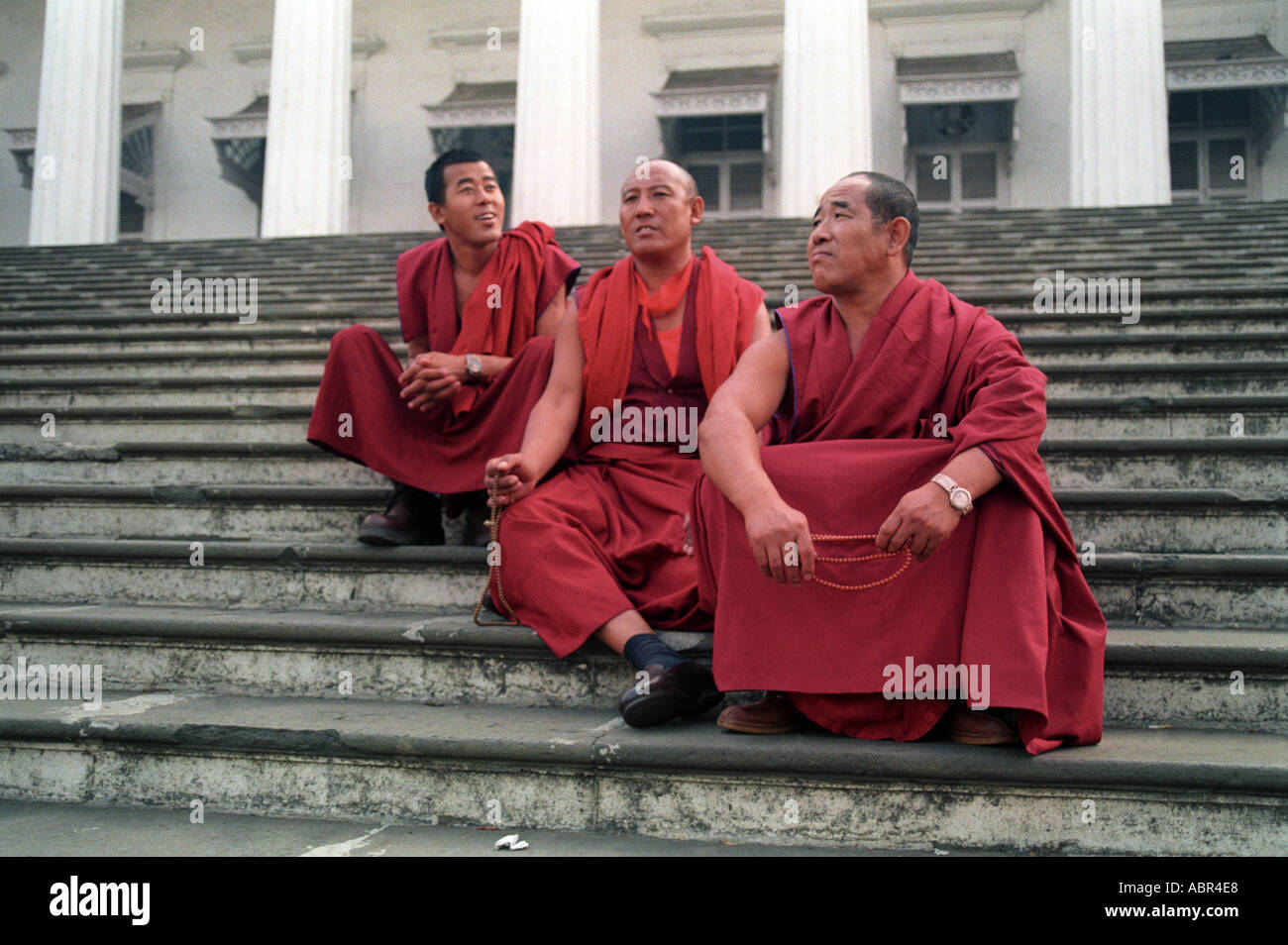 Three Tibetan monks sitting on the steps of Asiatic Library Mumbai ...