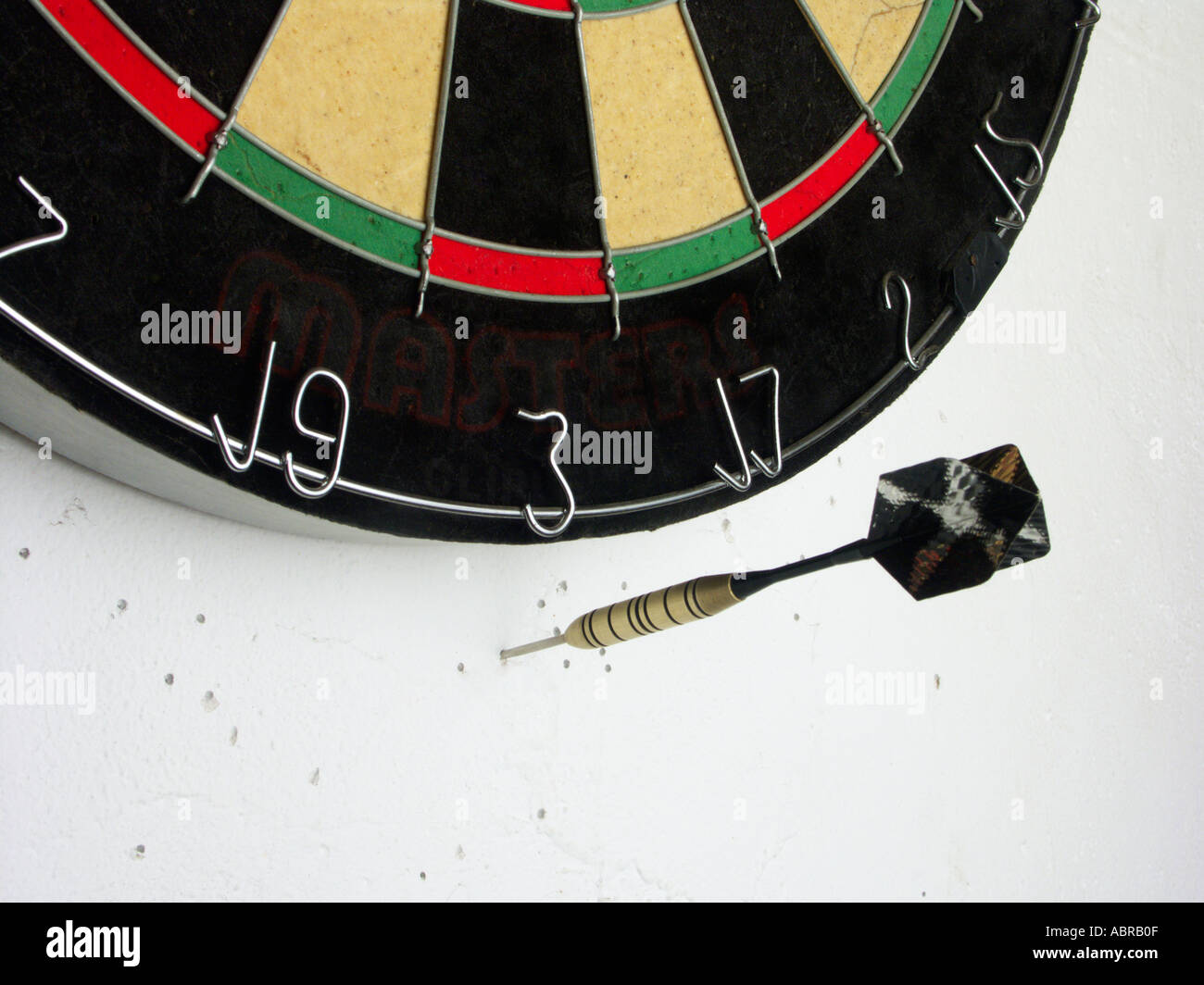A dartboard with a dart stuck in the wall next to it Stock Photo - Alamy