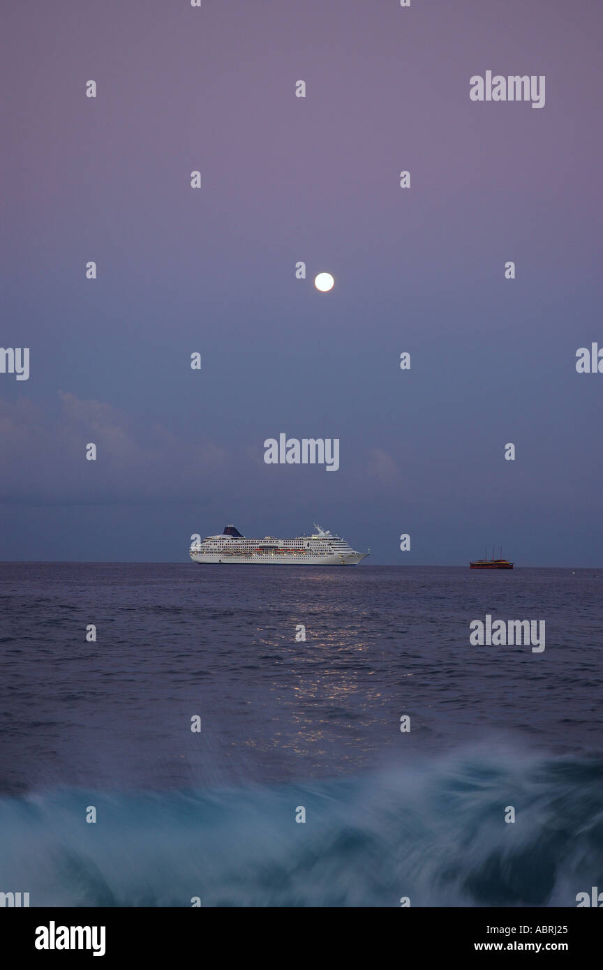 Full moon setting and cruise ship Wave breaking in the foreground ...