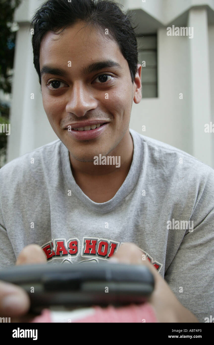 A wealthy Indian college student using his mobile phone to play a game ...