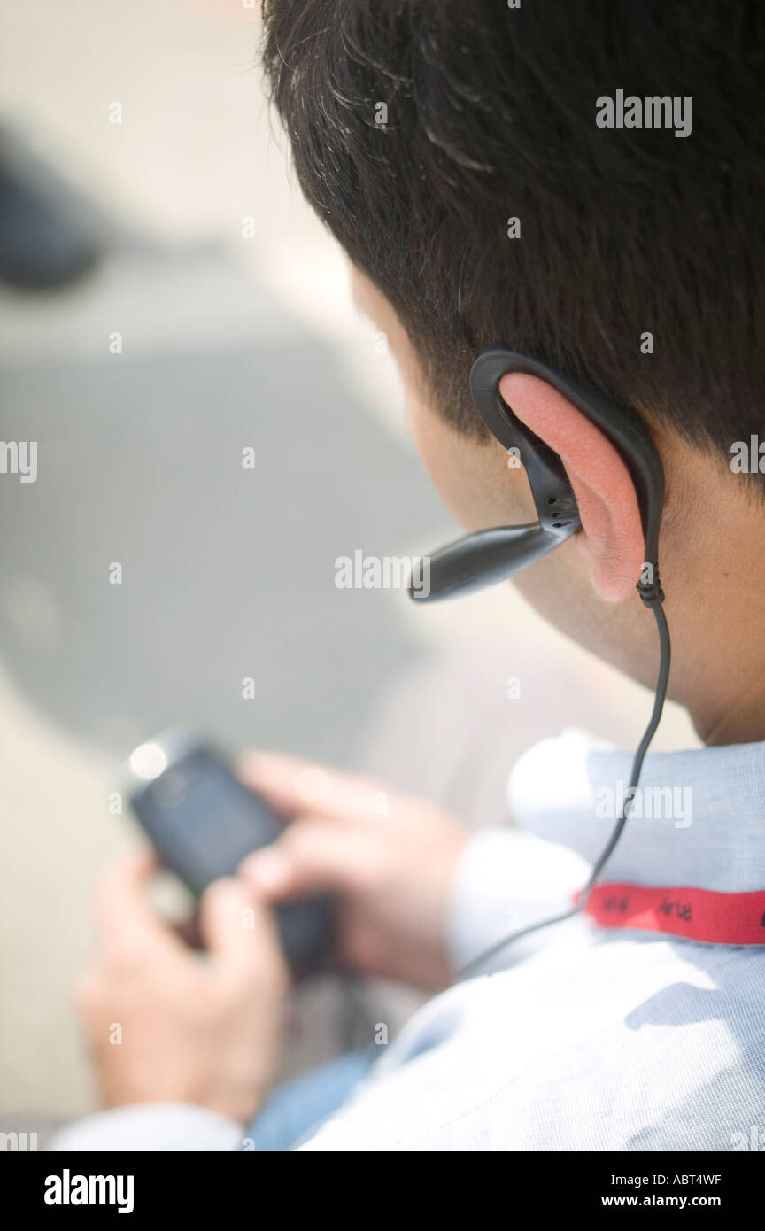 An Indian man using his mobile telephone with a headset attachment ...
