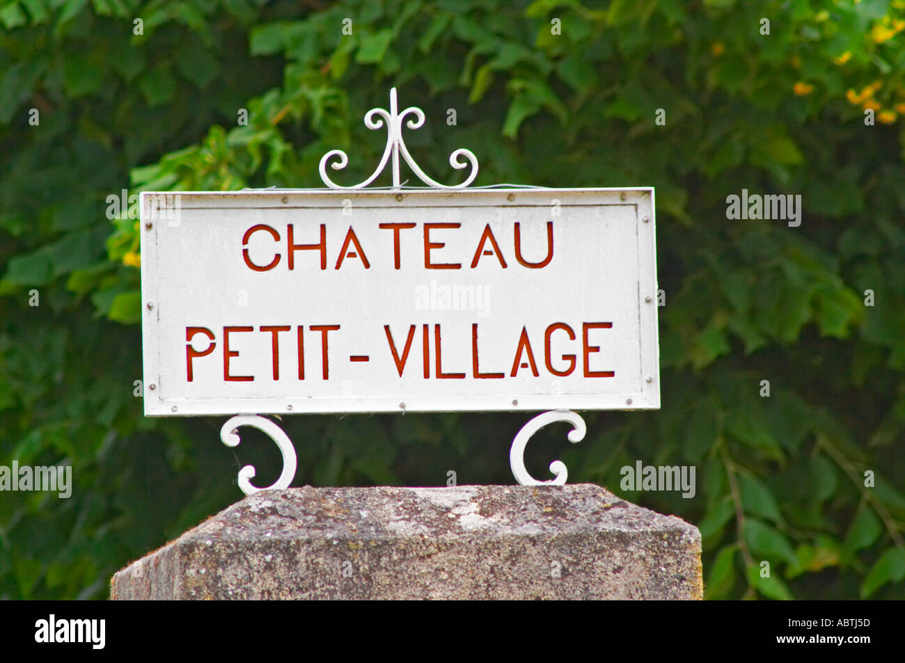 A stone gate post and a white sign saying Chateau Petit Village, detail ...