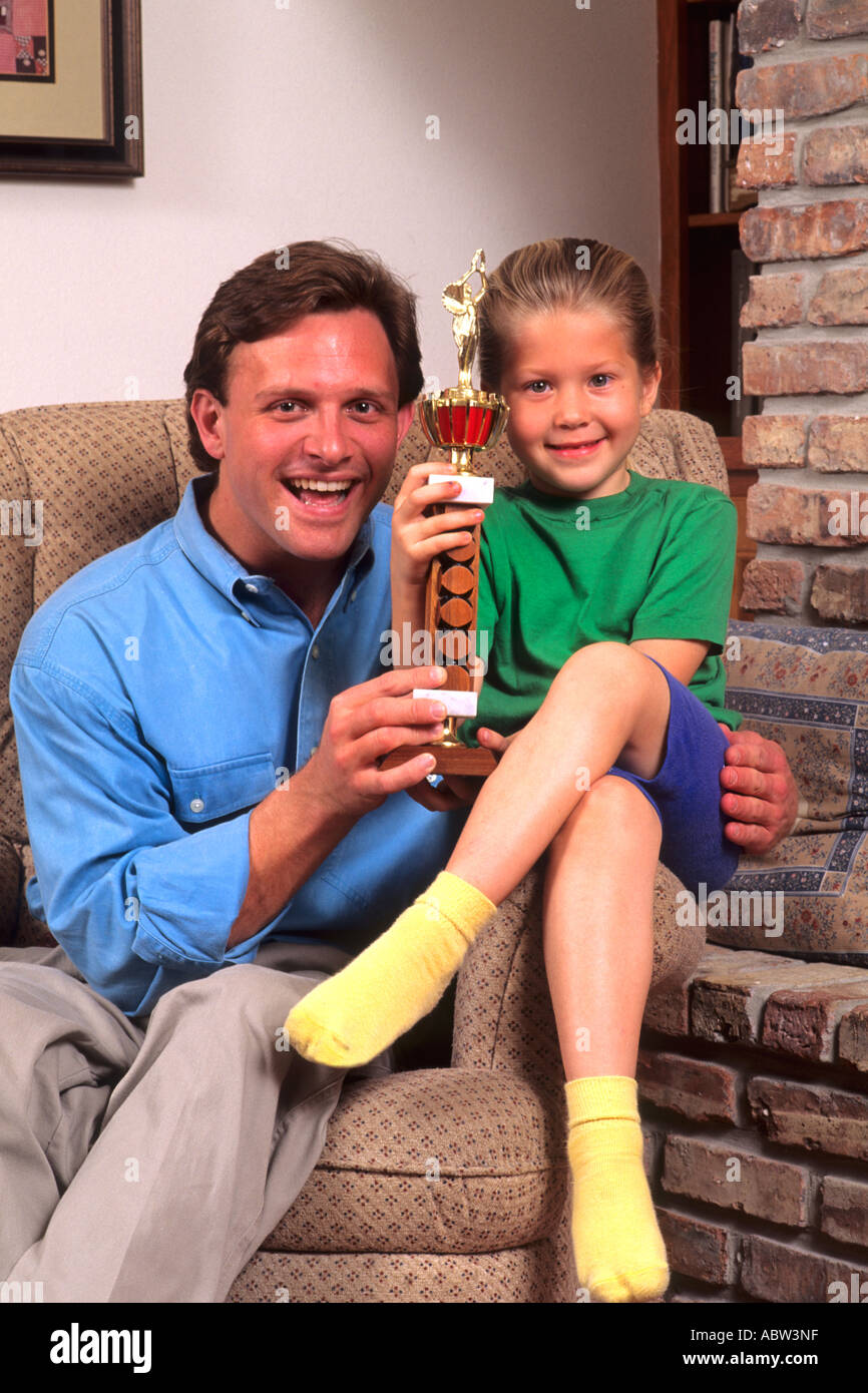Father and Daughter enjoy the fun of winning a trophy success at home ...