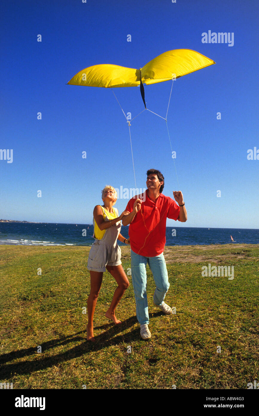 Romantic couple enjoy flying a stunt kite together on a beautiful sunny ...