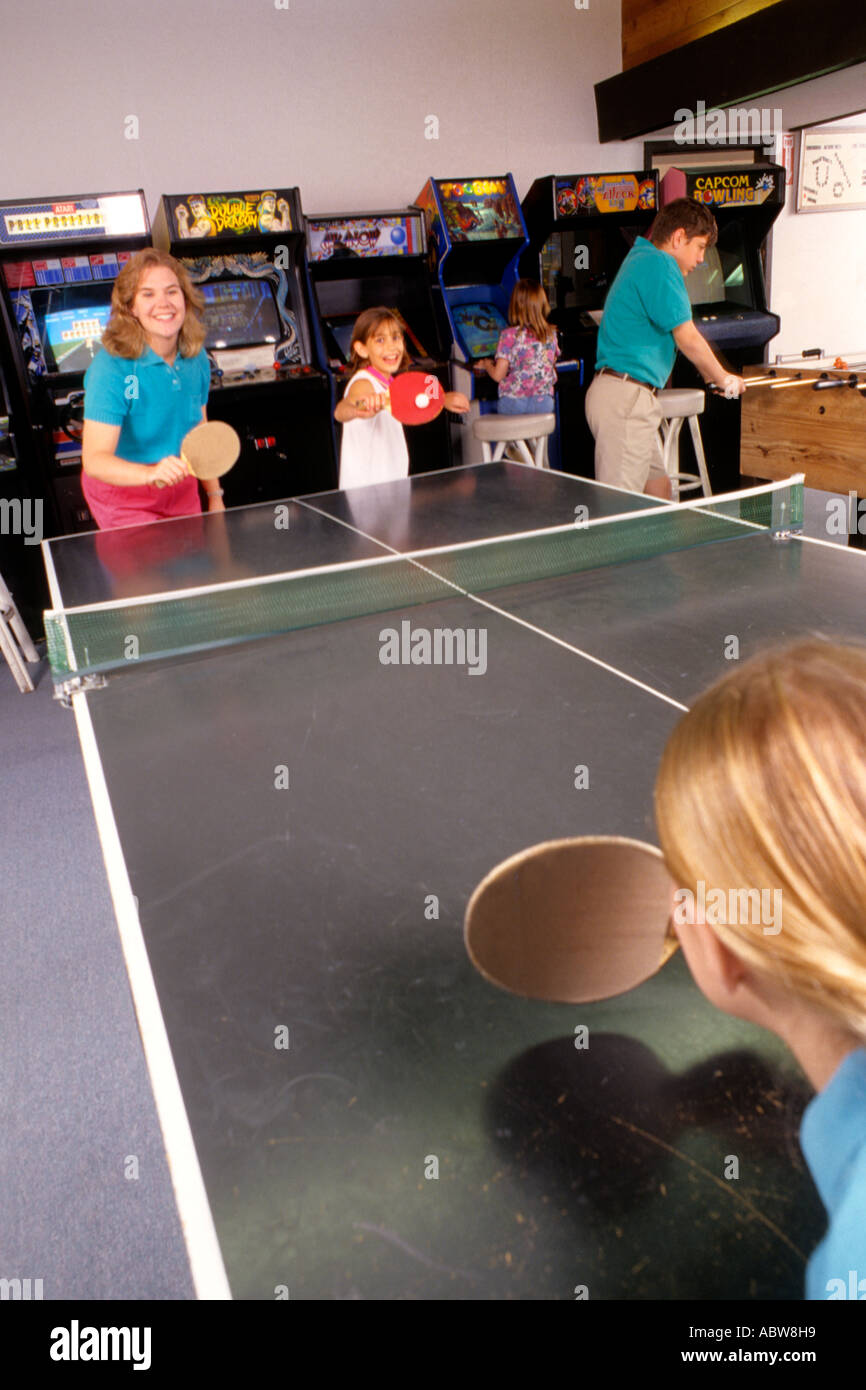 Family having fun together playing ping pong at arcade for excitement ...