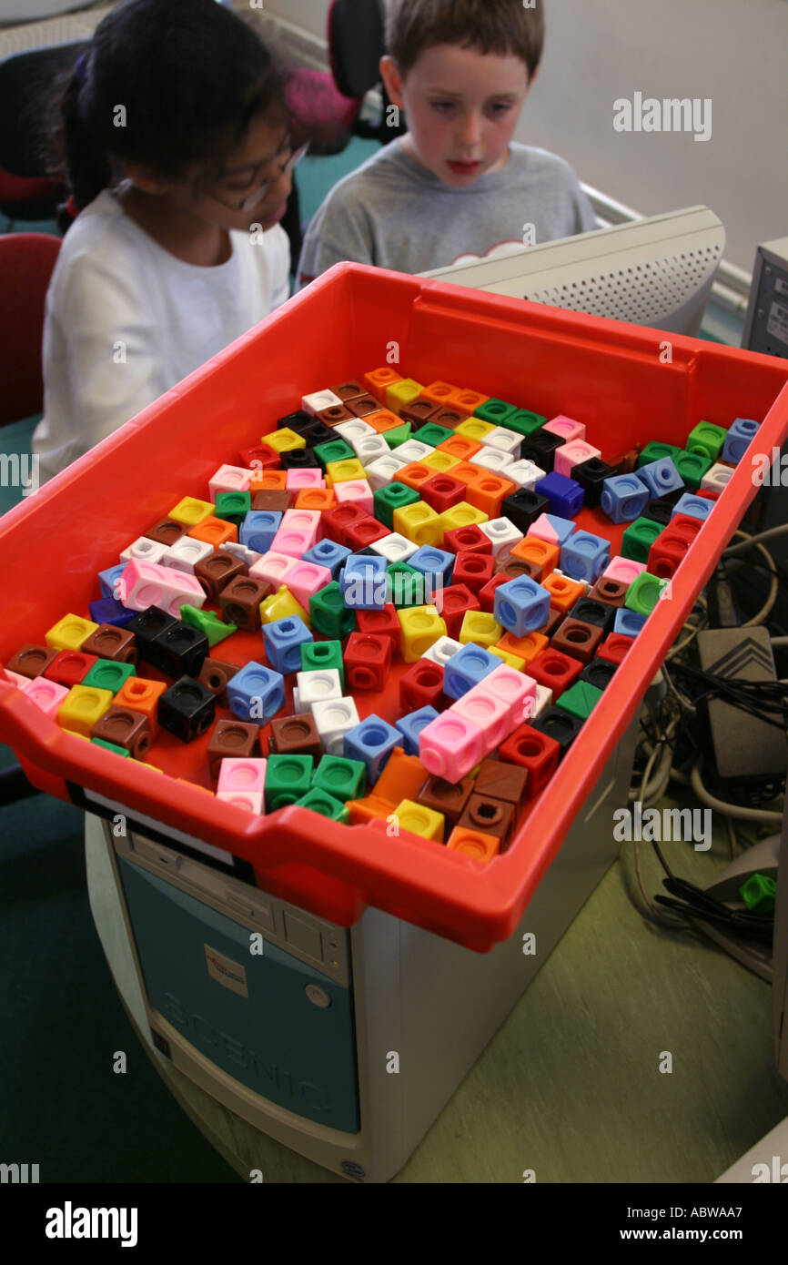 Children working on computers with traditional educational aids in the ...