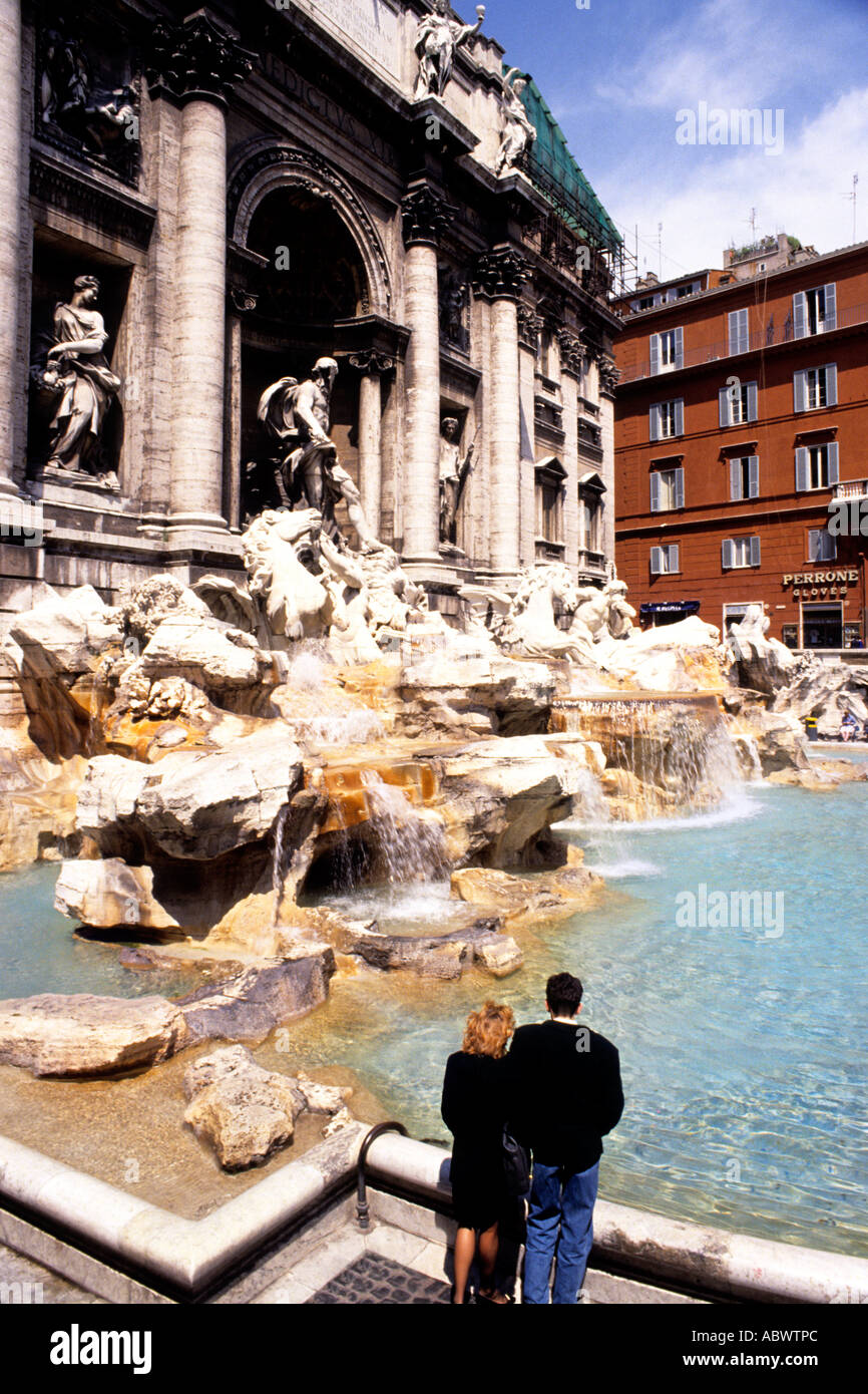 Couple tourists throwing coins into the famous Trevi Fountain to return ...