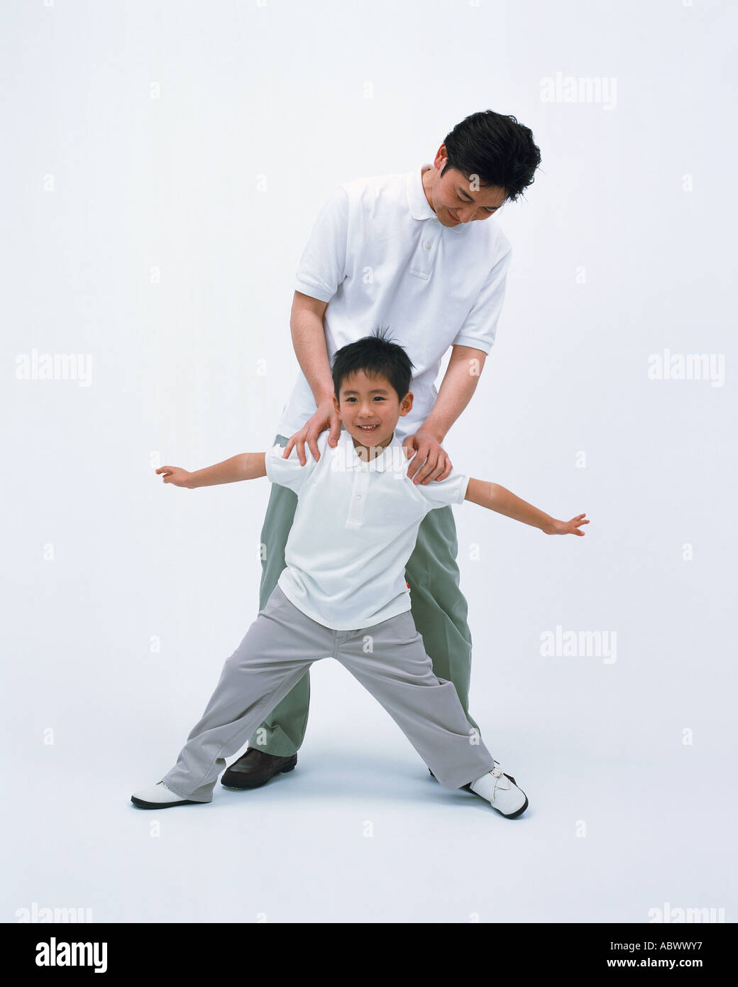 A small boy sprawling with his father standing behind him Stock Photo ...