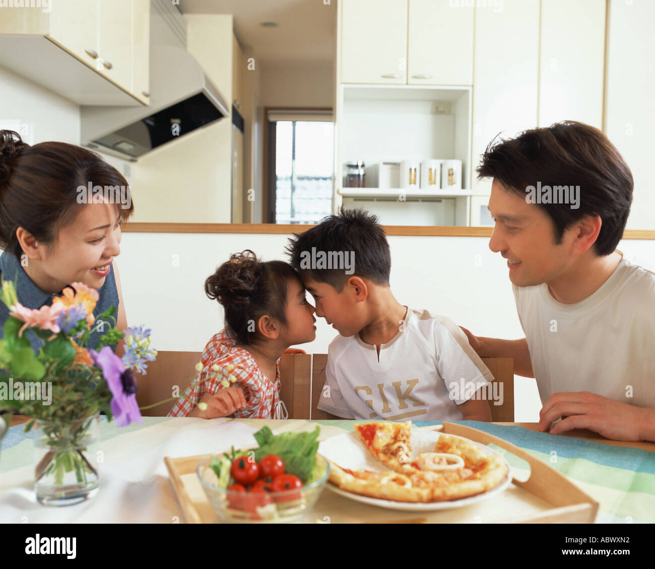 A brother and a sister having an eye contact while their parents look ...