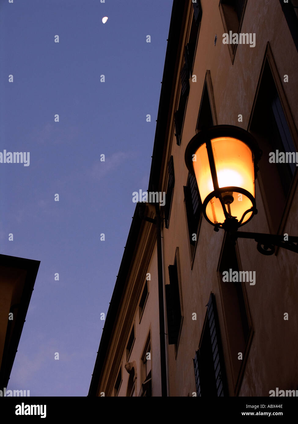 Moon overhead in deep blue early morning sky with street light and ...