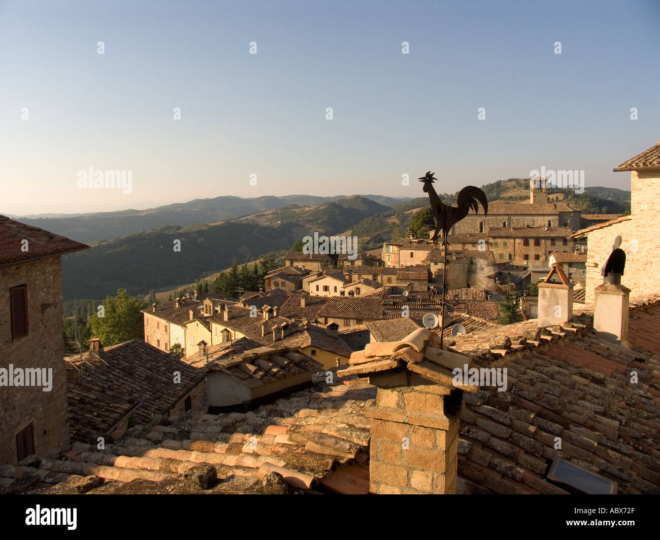 Black metal rooster weathervane looks out over rooftop view of the ...
