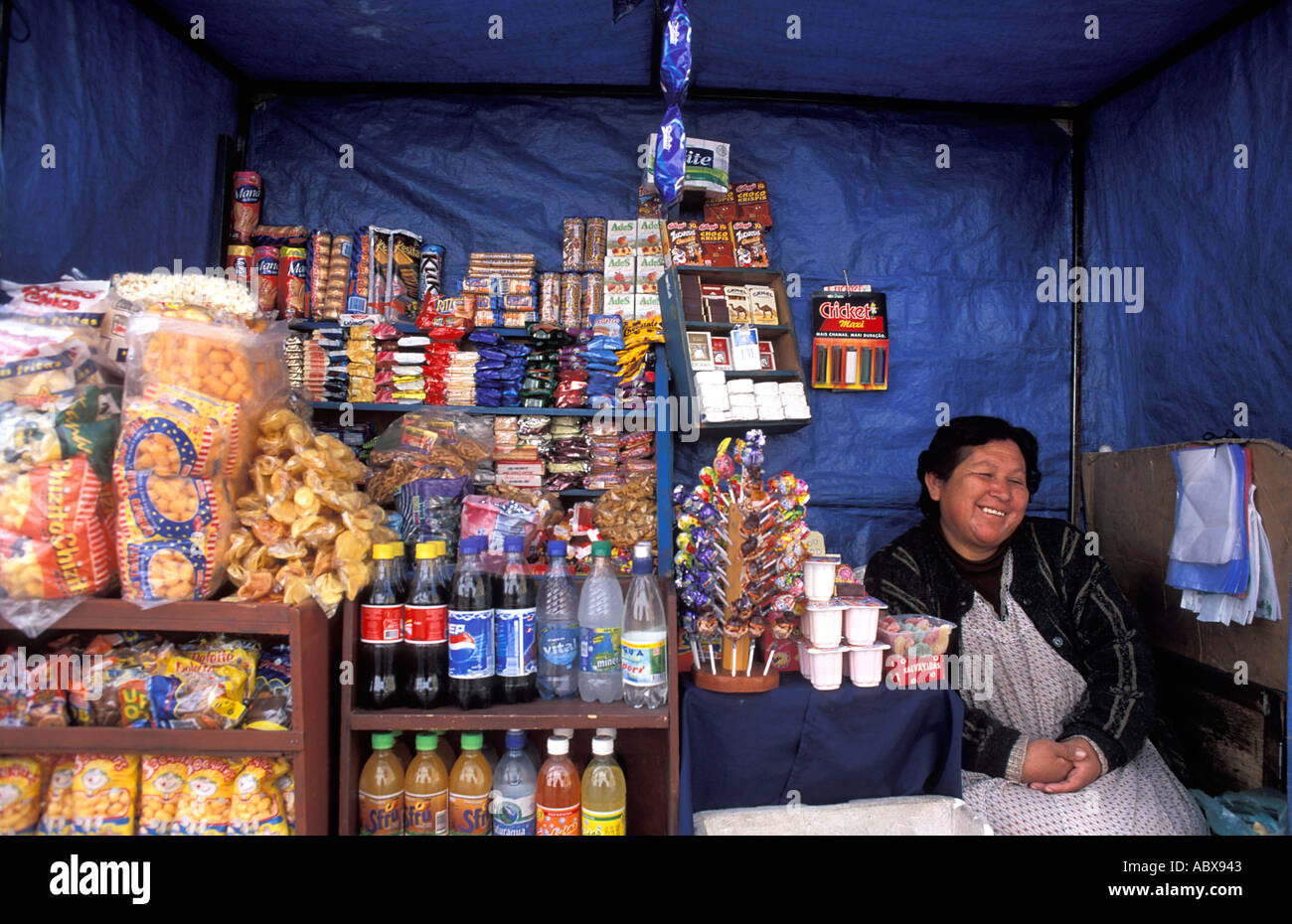 Friendly street vendor at her colorful stall selling snacks drinks and ...