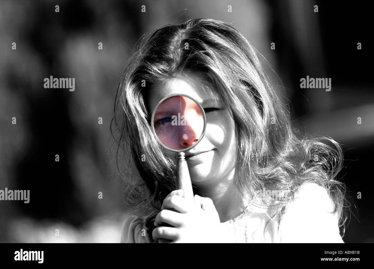 Girl looking through magnifying glass Stock Photo - Alamy