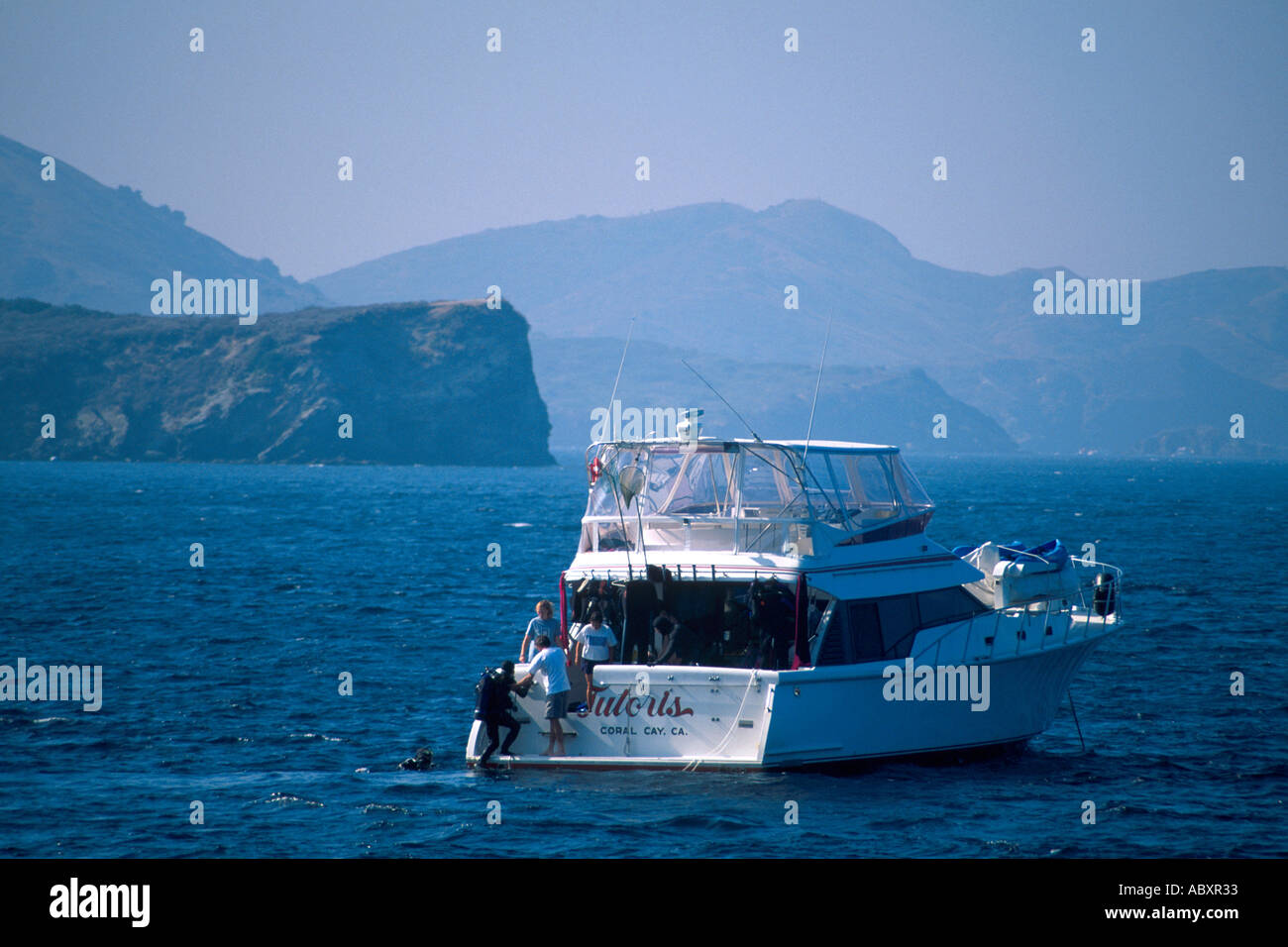 Scuba diver climbing onboard dive boat just offshore of Santa Catalina ...