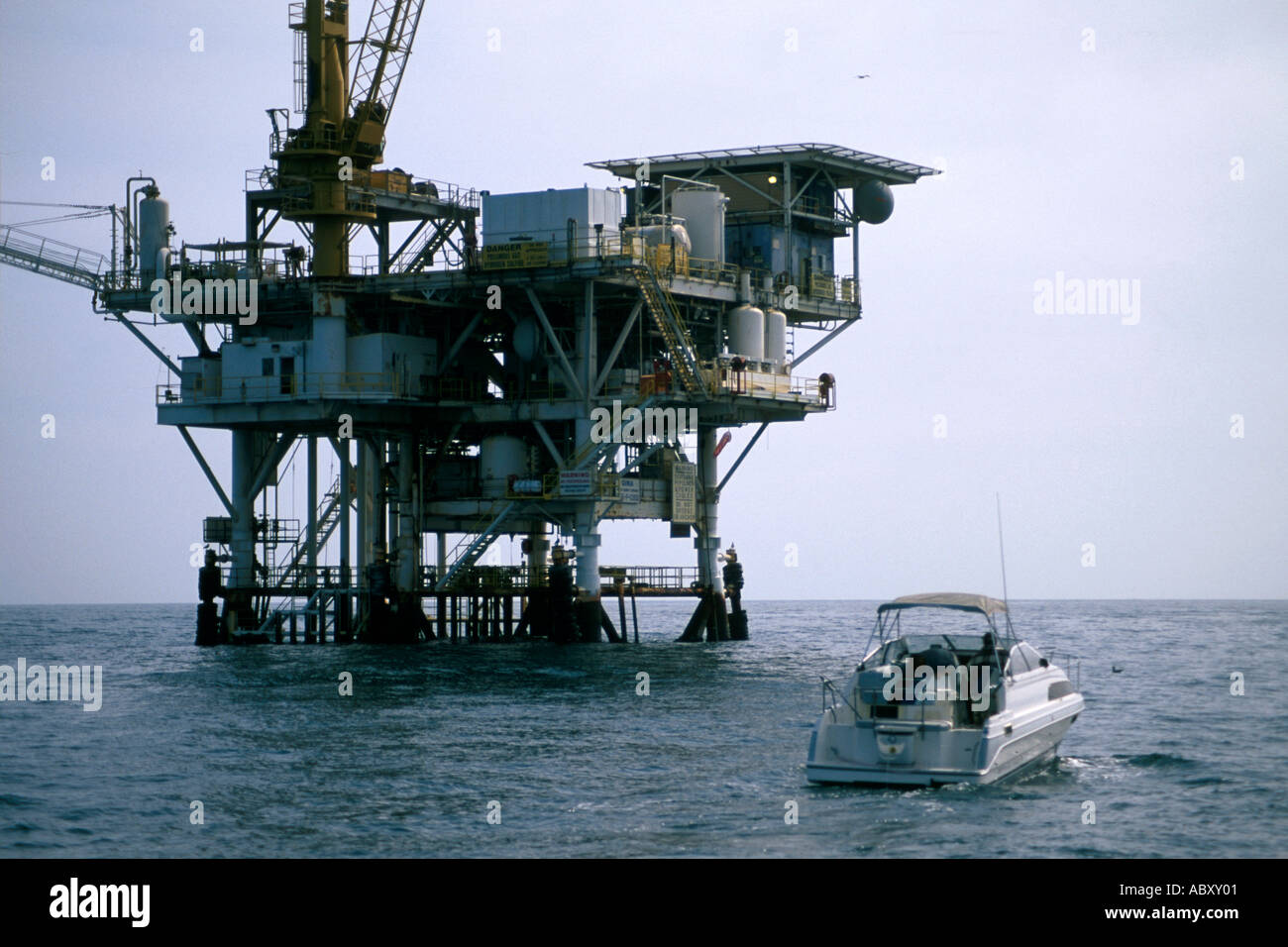 Recreational pleasure boat fishing next to oil drilling platform rig ...