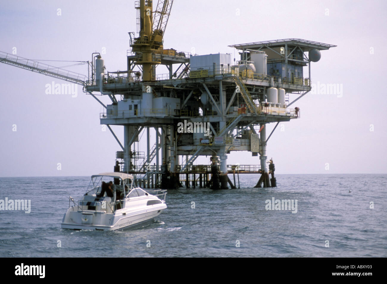 Recreational pleasure boat fishing next to oil drilling platform rig ...