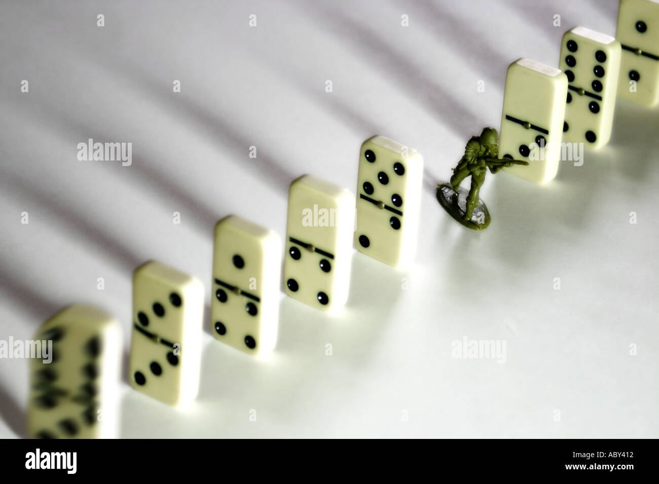 Toy soldier in a line of dominoes with motion blur to first domino ...